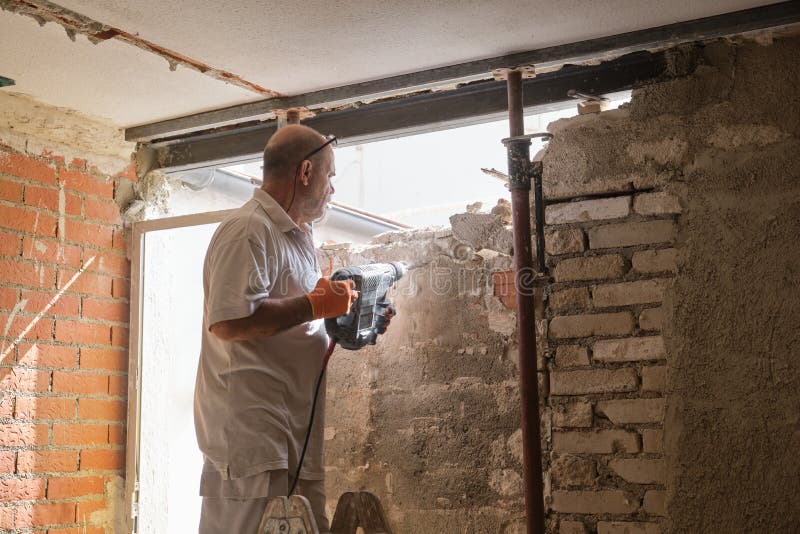 Builder with Demolition Hammer Breaking a House Wall. Stock Image ...