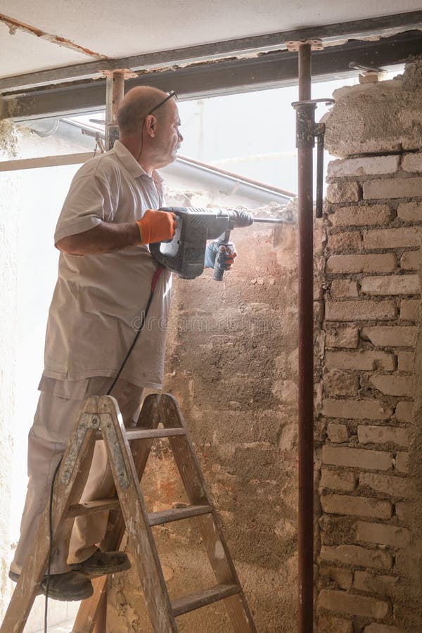 Builder with Demolition Hammer Breaking a House Wall. Stock Image ...