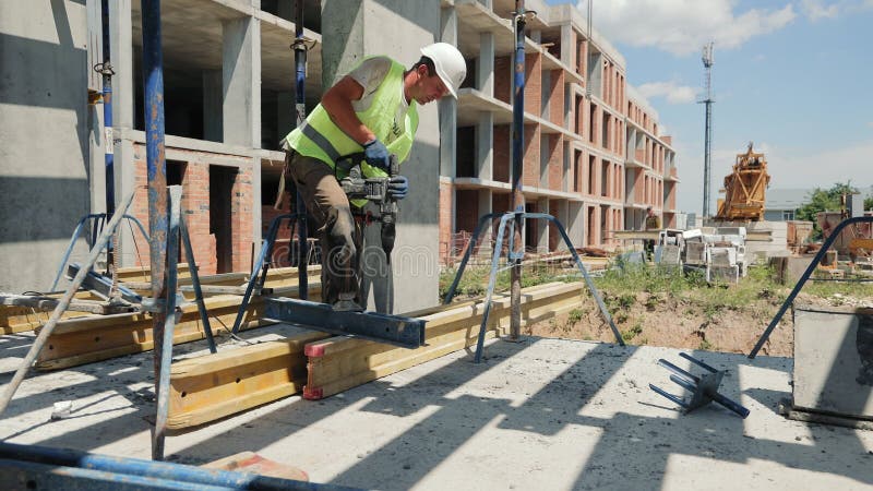 Construction Worker Drilling on Building Site. a Construction Worker is ...