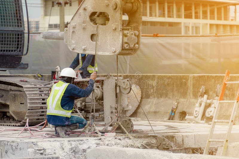 A Construction Worker in the Green Waistcoat and the White Helmet is ...