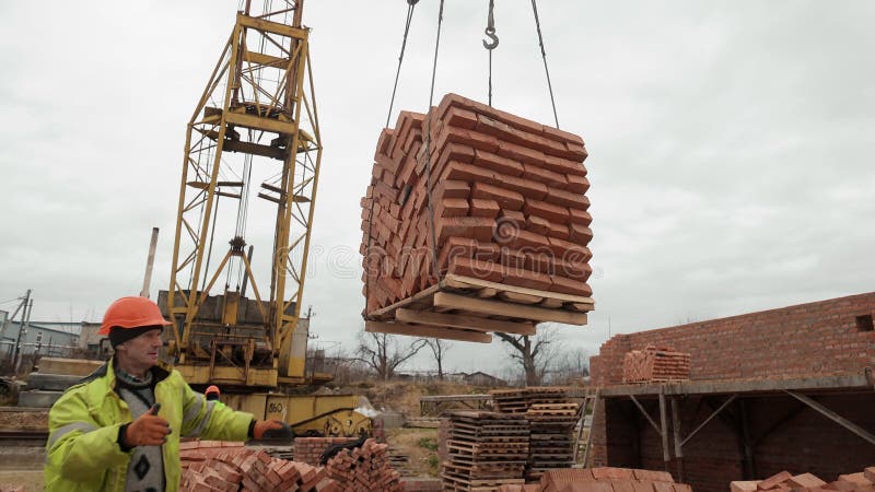 Construction Worker Guiding Crane Lifting Bricks, a Construction Worker ...