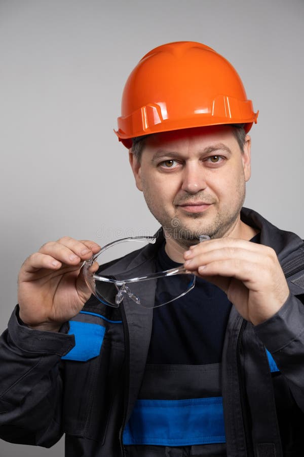 A Construction Worker in a Helmet and Overalls Put on Goggles ...