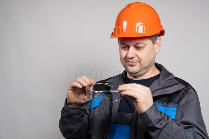 A Construction Worker in a Helmet and Overalls Put on Goggles ...
