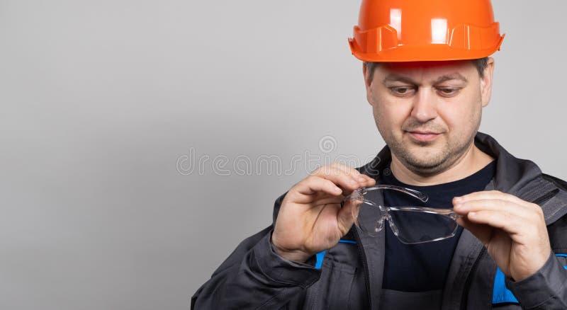 A Construction Worker in a Helmet and Overalls Put on Goggles ...