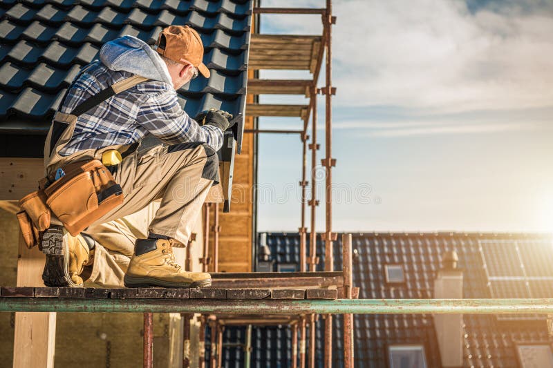 Construction Worker Inspecting Tools while Kneeling on Scaffolding at a ...