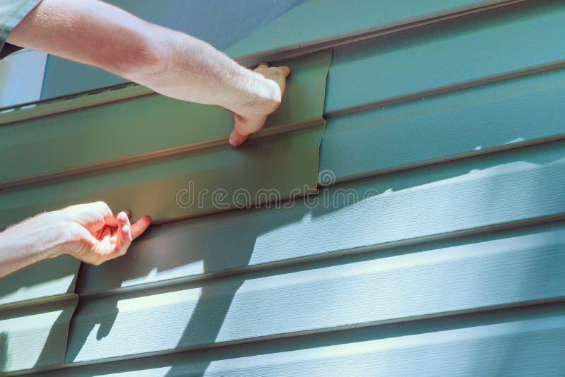 During Construction, Worker Installs Vinyl Plastic Siding Panels on a ...