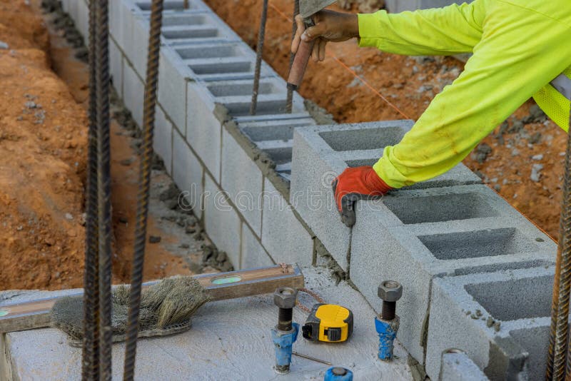 Construction Worker Laying Another Row of Cement Blocks on the Ground ...