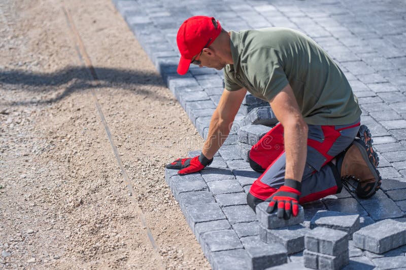 Construction Worker Laying Paving Stones on a Pathway at a Construction ...