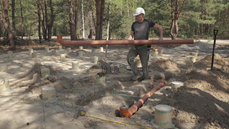 Construction Worker Laying Underground Pipes in a Forested Area during ...