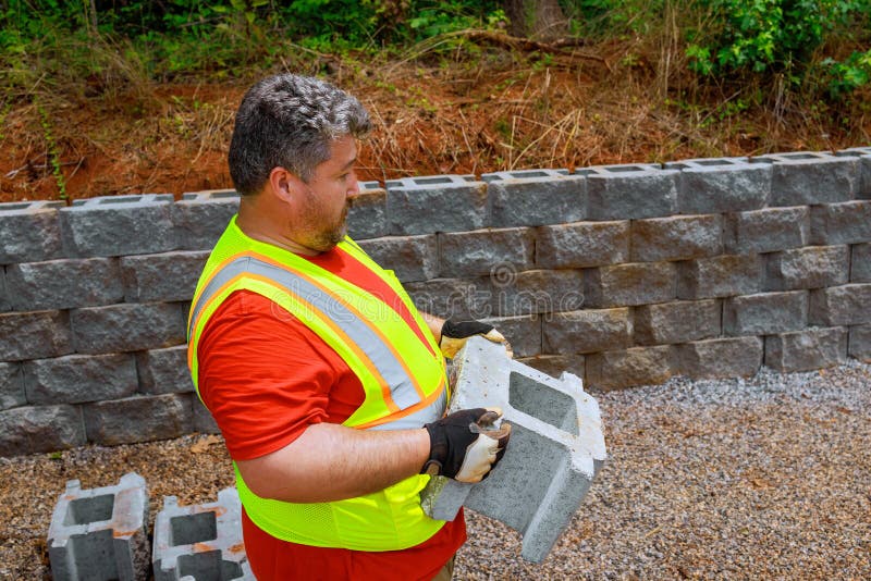 In Construction Plase, a Worker Lifts Concrete Blocks and Positions ...