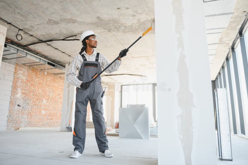 Construction Worker Painting Wall with Roller in Building Under ...