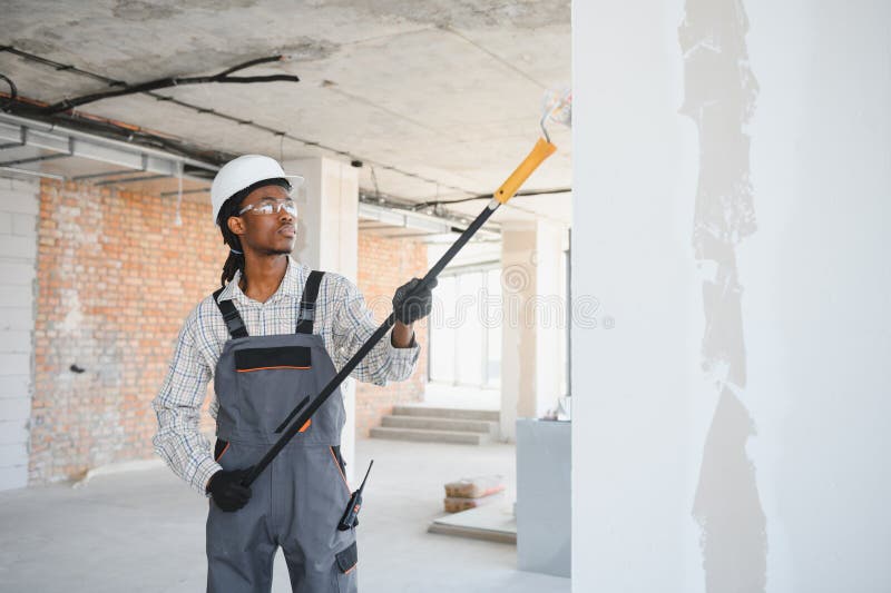 Construction Worker Painting Wall with Roller in Building Under ...