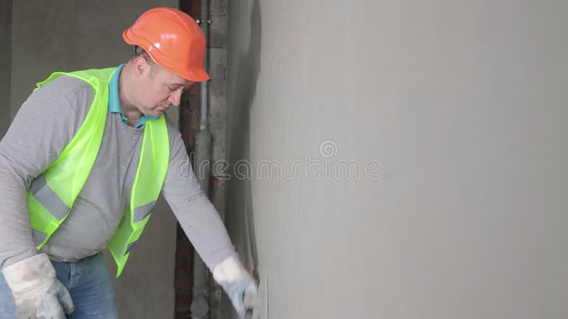 Construction Worker Plastering a Wall Indoors, Wearing a Hard Hat and a ...