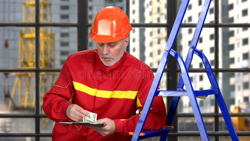 Construction Worker in Red Uniform and Orange Hardhat Writing Something ...