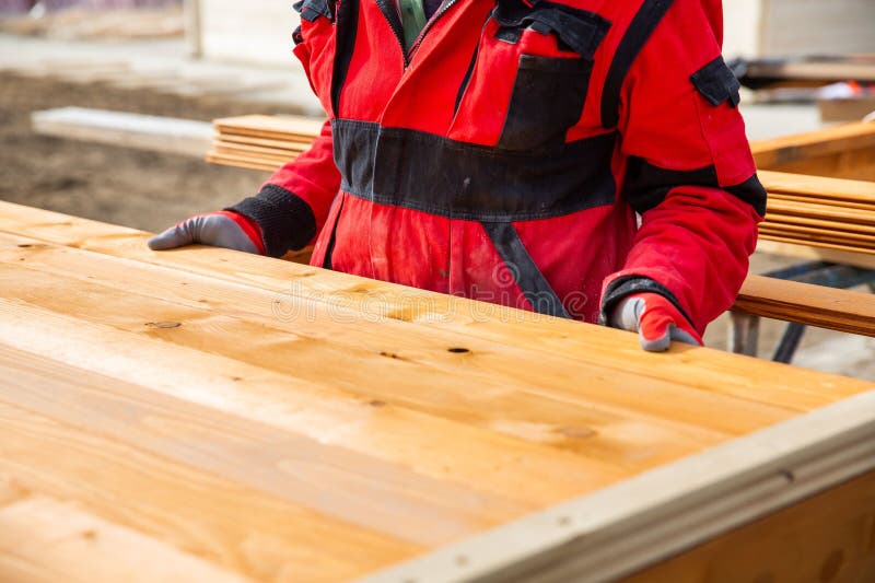 Construction Worker in Red Workwear Working with a Wooden Structure on ...
