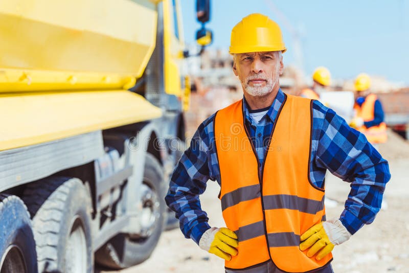 Worker in Reflective Vest and Hardhat Standing with Hands on Waist at ...