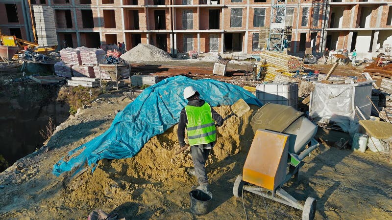 Construction Worker in Safety Gear Mixing Cement on a Building Site ...