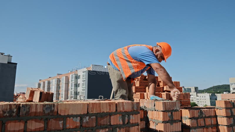 Construction Worker Stacking Bricks on Rooftop Wall. Builder in Safety ...