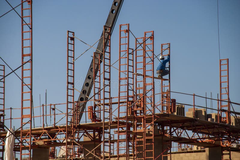 A Construction Worker Standing on Metal Scaffolding Against a Blue Sky ...