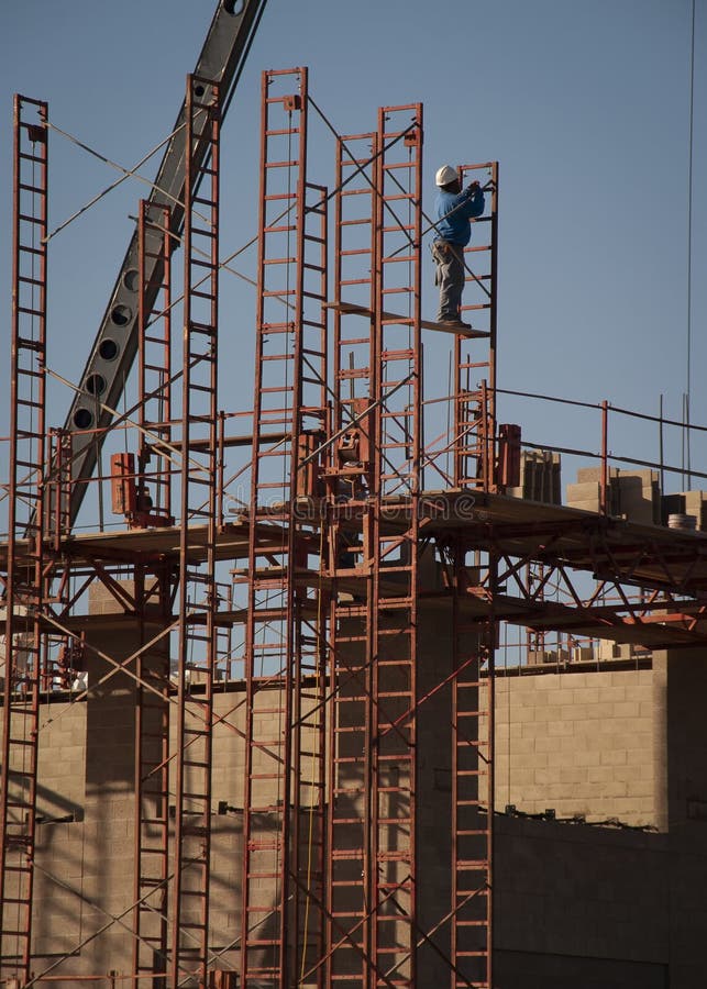 A Construction Worker Standing on Metal Scaffolding Against a Blue Sky ...