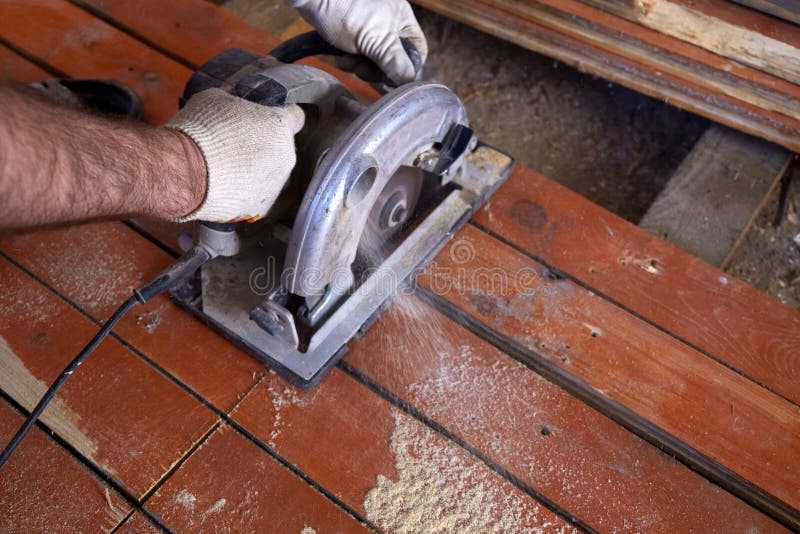 A Construction Worker Uses a Circular Saw To Cut Wooden Planks in a ...