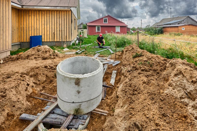 Construction Worker Uses Winch To Lower Concrete Septic Tank Ring into ...