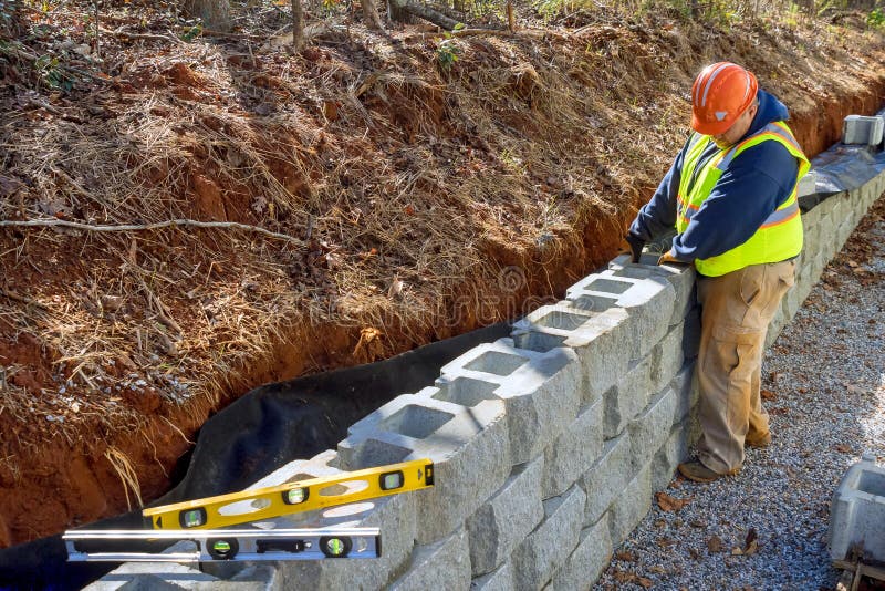 Construction Worker is Using Cement Blocks for Building a Retaining ...