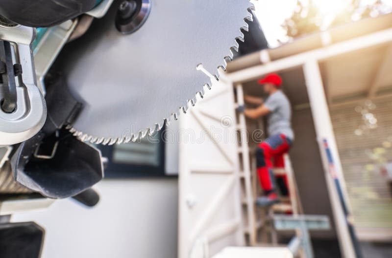 Construction Worker Using a Circular Saw while Standing on a Ladder at ...