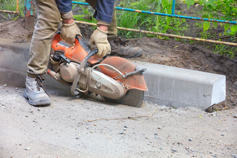 A Construction Worker Using a Portable Gasoline Saw Cuts a Concrete ...