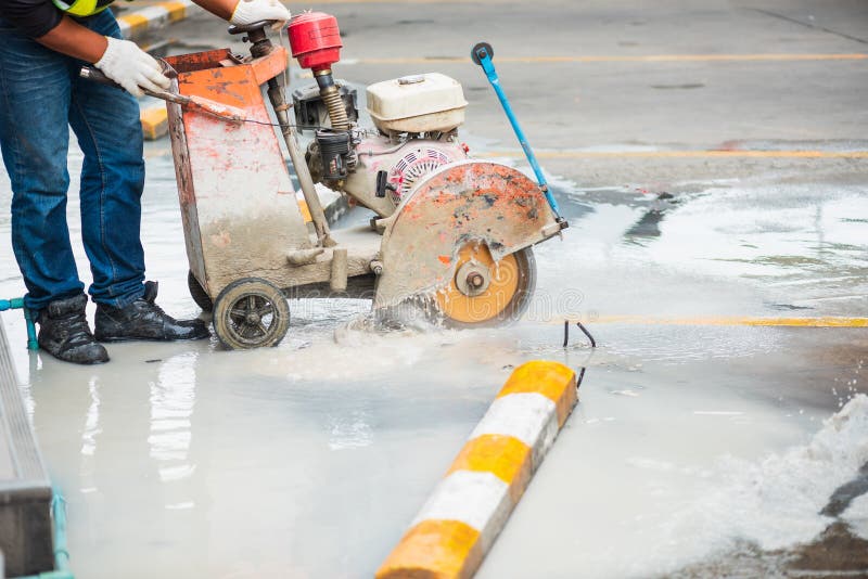 A Construction Worker is Using a Concrete Saw To Cut through a Wet ...
