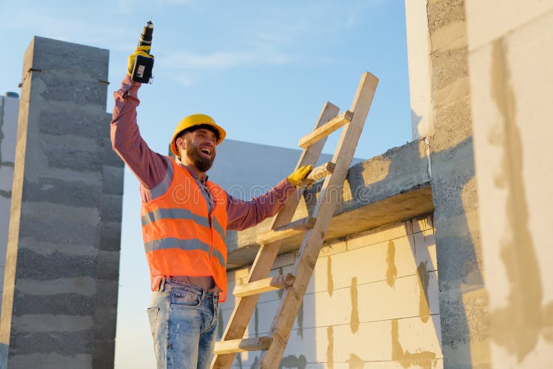 Construction Worker Using Cordless Drill on Wooden Ladder at Building ...