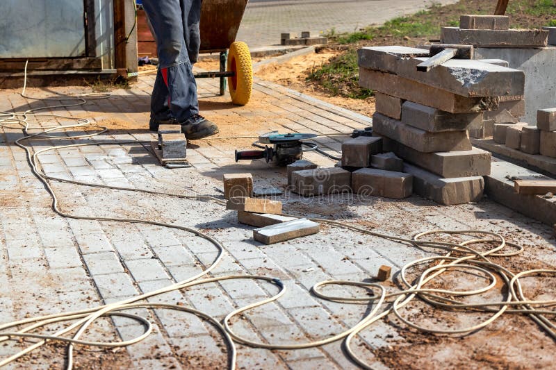 A Construction Worker Using an Electric Grinder and a Diamond Cutting ...