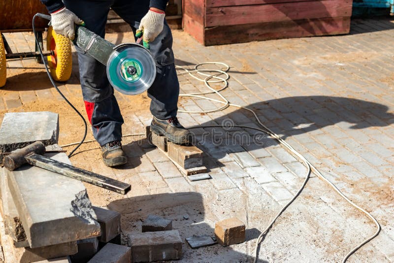 A Construction Worker Using an Electric Grinder and a Diamond Cutting ...