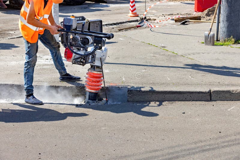 Construction Worker Using Equipment To Break Concrete on a Sunny Day ...