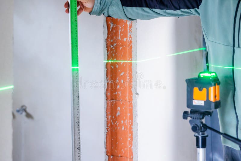 Construction Worker Using Laser Level and Ruler Taking Measurements on ...