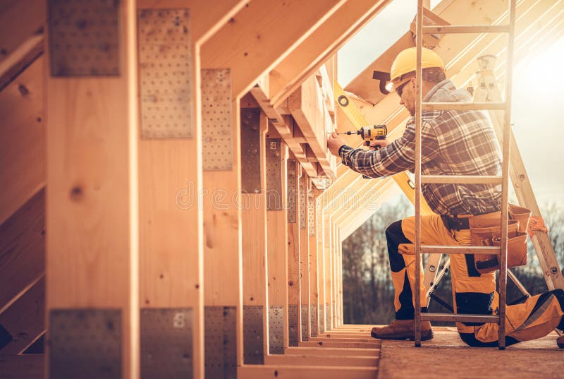 Construction Worker Using a Power Drill on a Wooden Frame in a ...