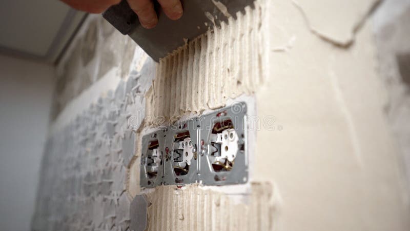 Construction Worker Applying Plaster on Wall Around Electrical Outlets ...