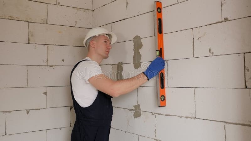 Construction Worker in White Hardhat Checking Level of Wall with the ...