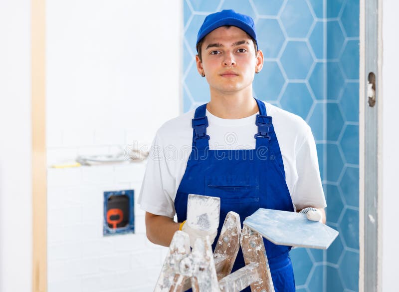 Construction Worker in Work Clothes Engaged in Wall Tiling Work during ...