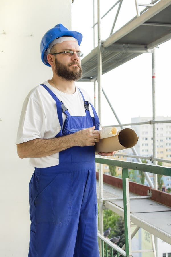 Construction Worker in a Work Outfit and in a Helmet Stands at a High ...