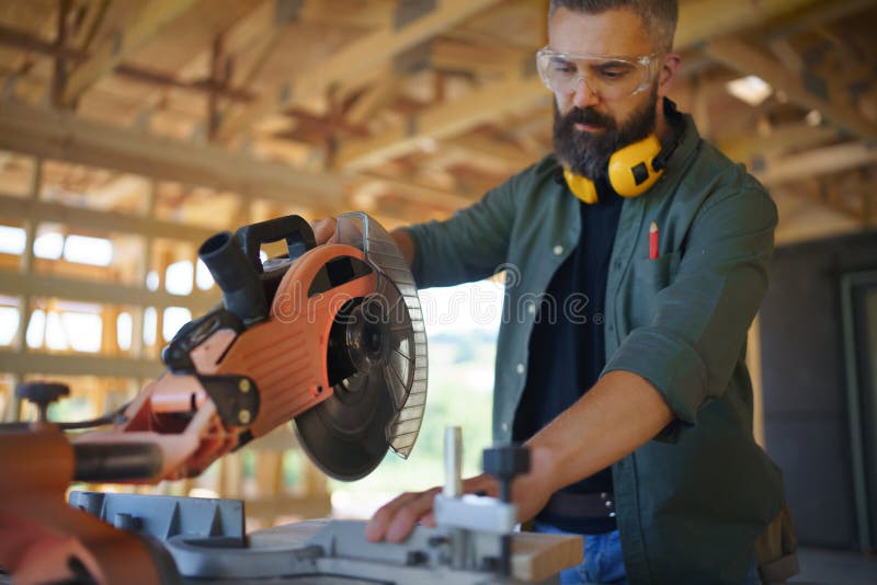 Construction Worker Working with Eletric Saw Inside Wooden Construction ...