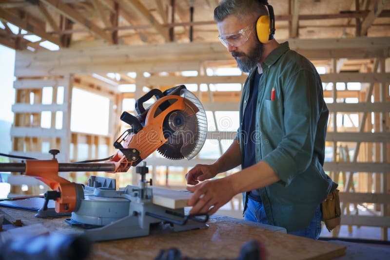 Construction Worker Working with Eletric Saw Inside Wooden Construction ...
