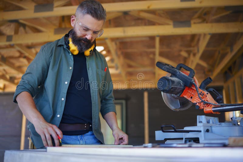 Construction Worker Working with Eletric Saw Inside Wooden Construction ...