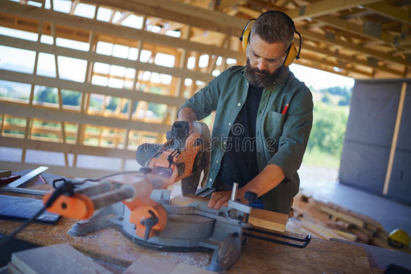 Construction Worker Working with Eletric Saw Inside Wooden Construction ...