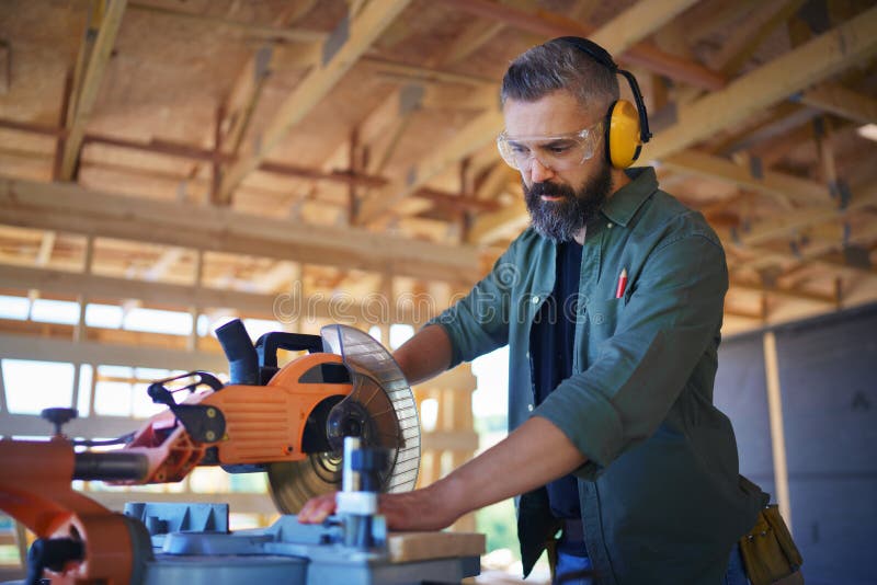 Construction Worker Working with Eletric Saw Inside Wooden Construction ...