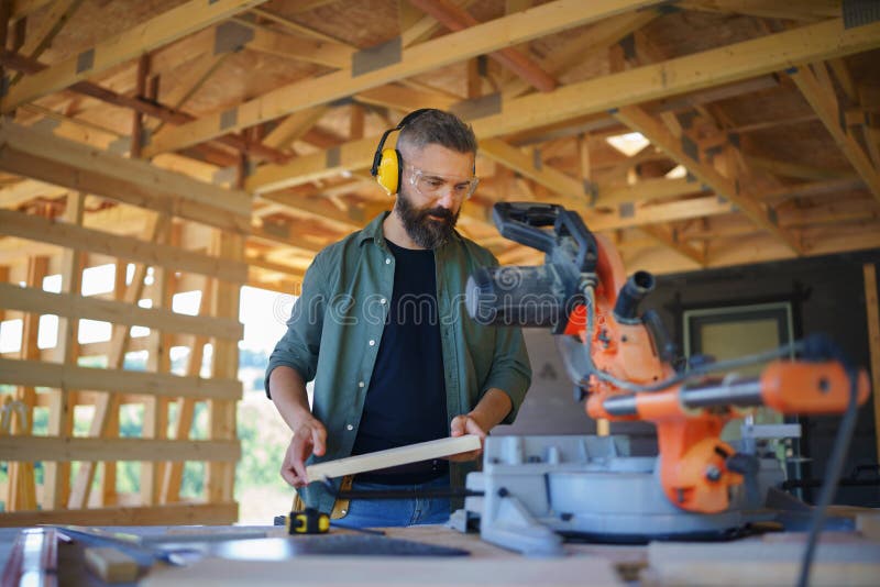 Construction Worker Working with Eletric Saw Inside Wooden Construction ...