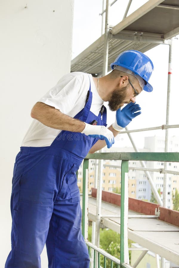 Construction Worker in Working Outfit and in Protective Helmet Stands ...
