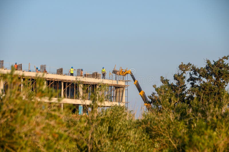 Construction Workers Building a Structure Under Clear Blue Sky in a ...