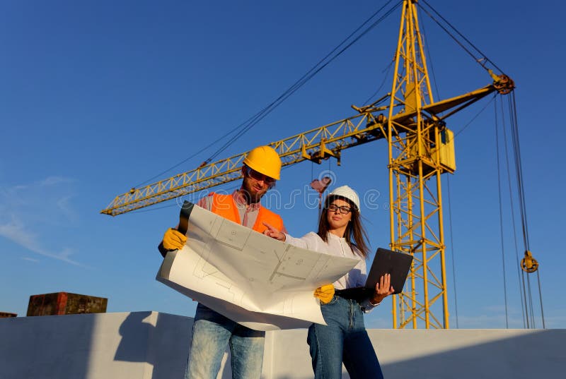 Construction Workers Discussing Blueprint on Building Site with Crane ...