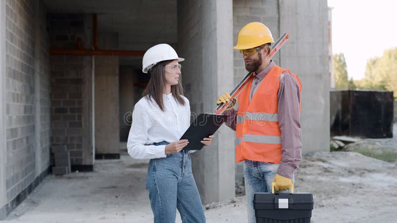 Construction Workers Discuss Project Plans at a Busy Construction Site Under Clear Blue Skies ...